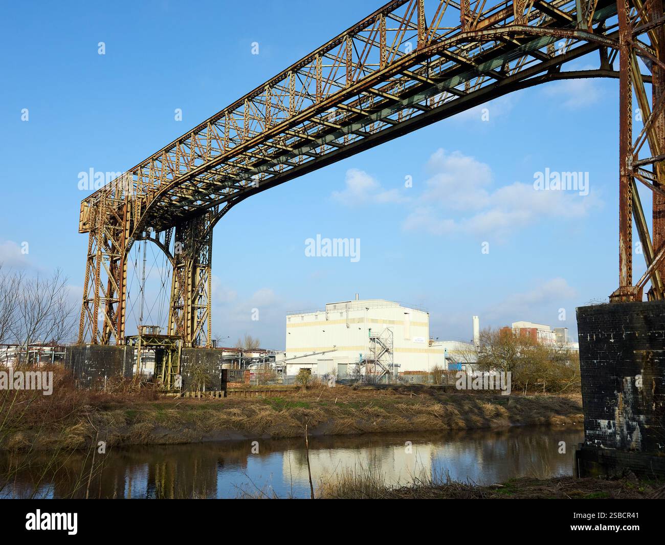 Rustic industrial bridge with blue sky backdrop and tranquil river ...