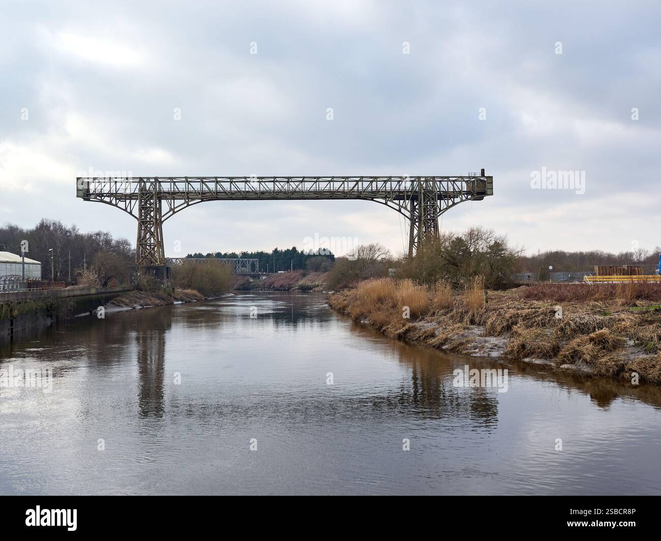 Historic bridge spanning over a calm river during a cloudy day ...