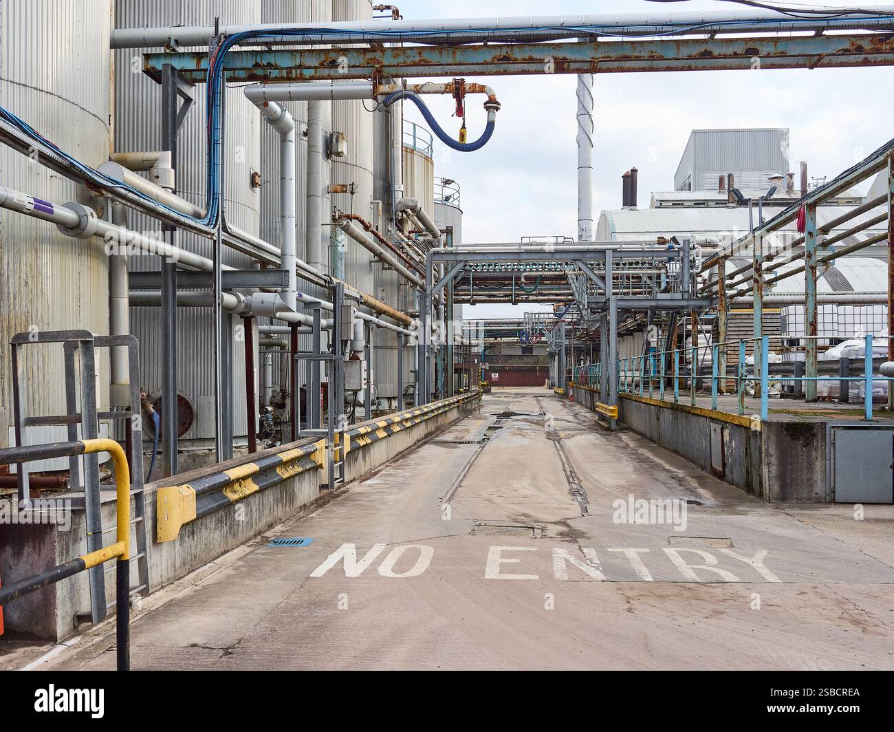 Industrial chemical facility with 'No Entry' sign on a deserted pathway ...