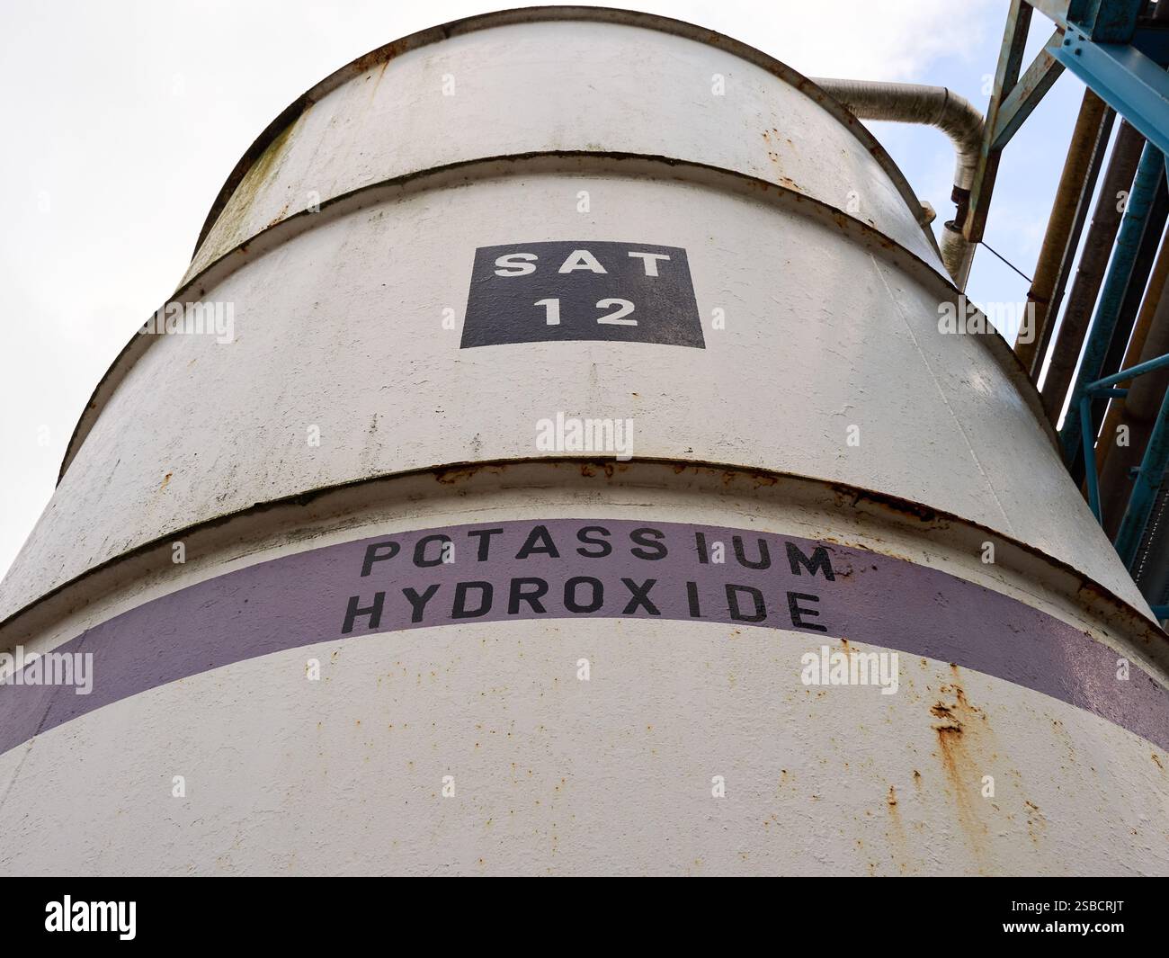 Industrial chemical tank labeled 'Potassium Hydroxide' against a cloudy ...