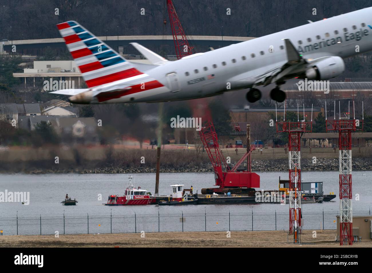 An American Eagle jet passes as rescue and salvage crews work near the ...