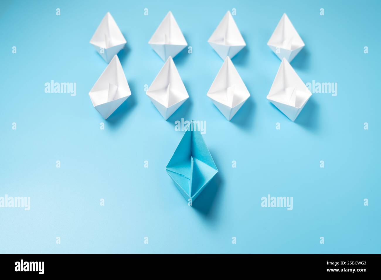Leadership concept with blue paper ship leading among white boats ...