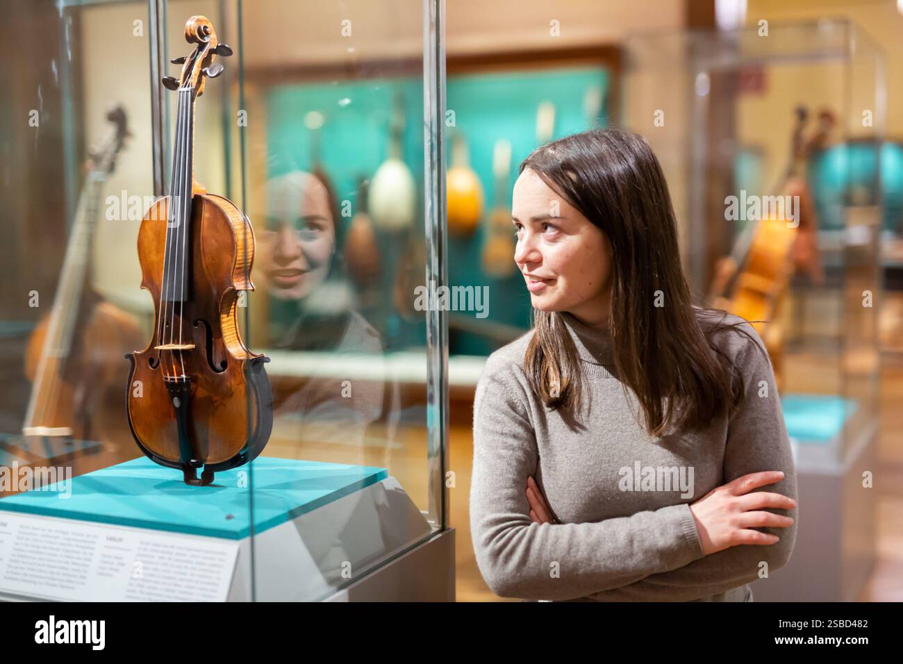 Interested brunette visiting exhibition of medieval musical instruments ...