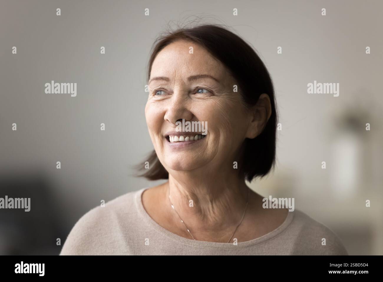 Smiling mature female looks into distance with dreamy expression Stock ...