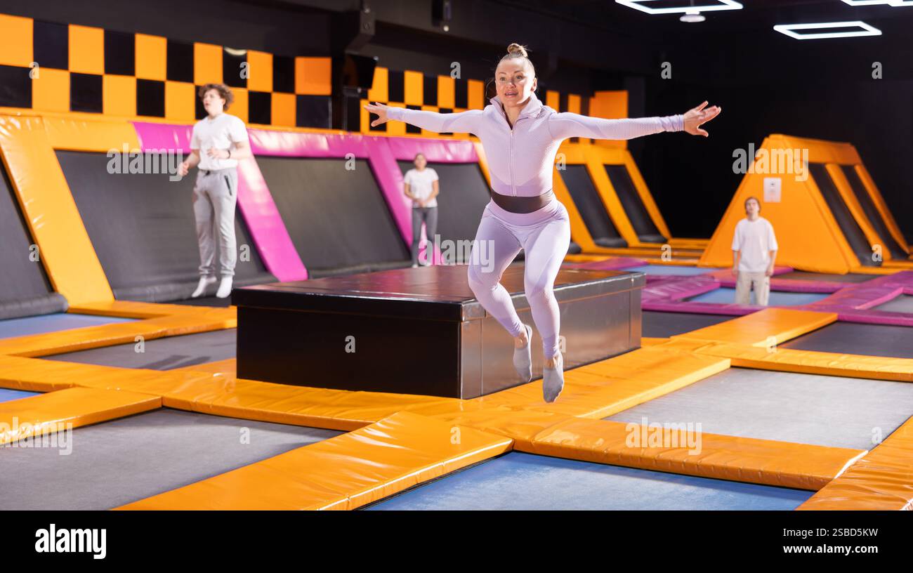 Adult woman trains jumping in trampoline center Stock Photo - Alamy