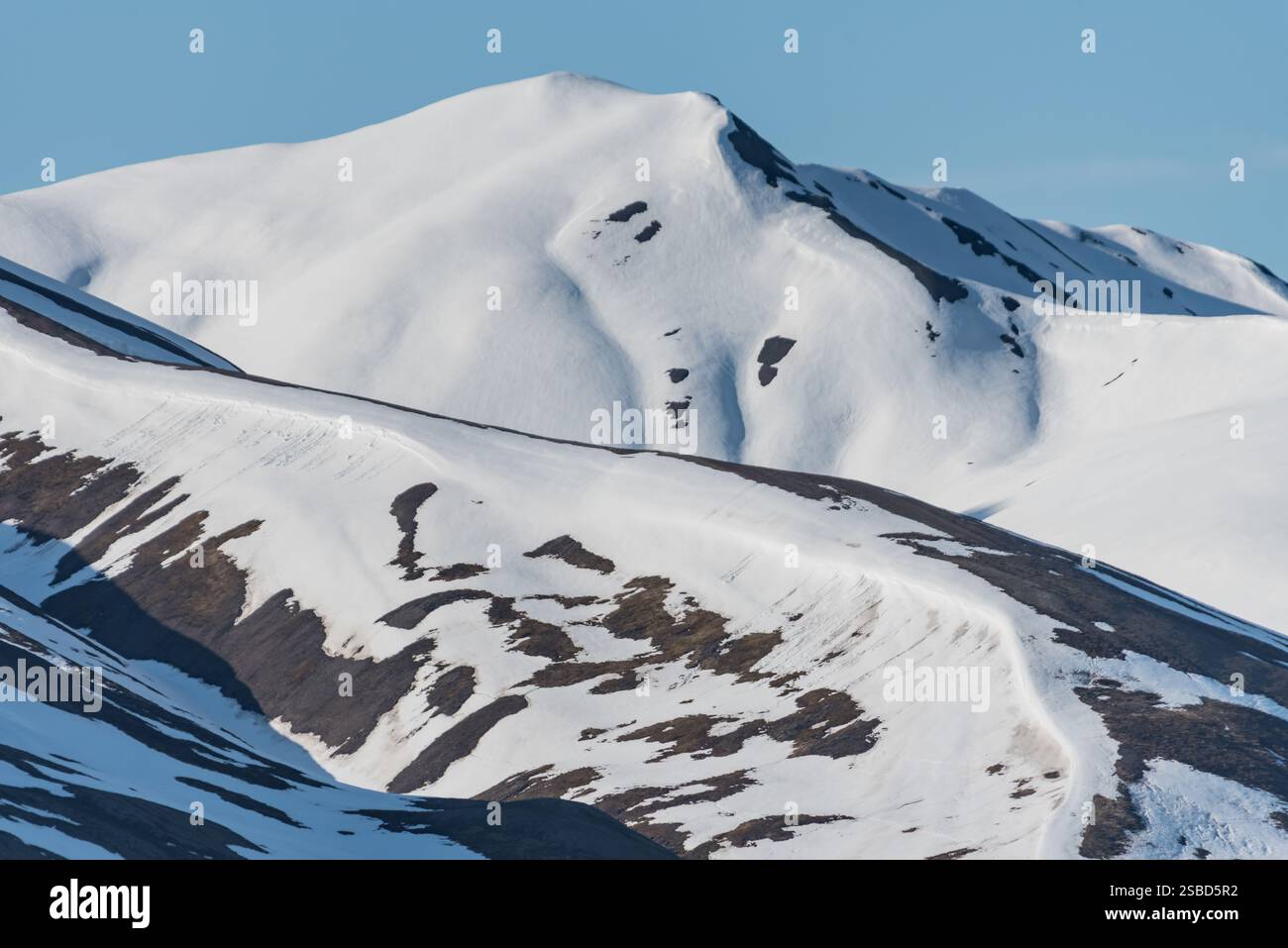 Snow covered mountains with rocky patches in the arctic in Svalbard ...