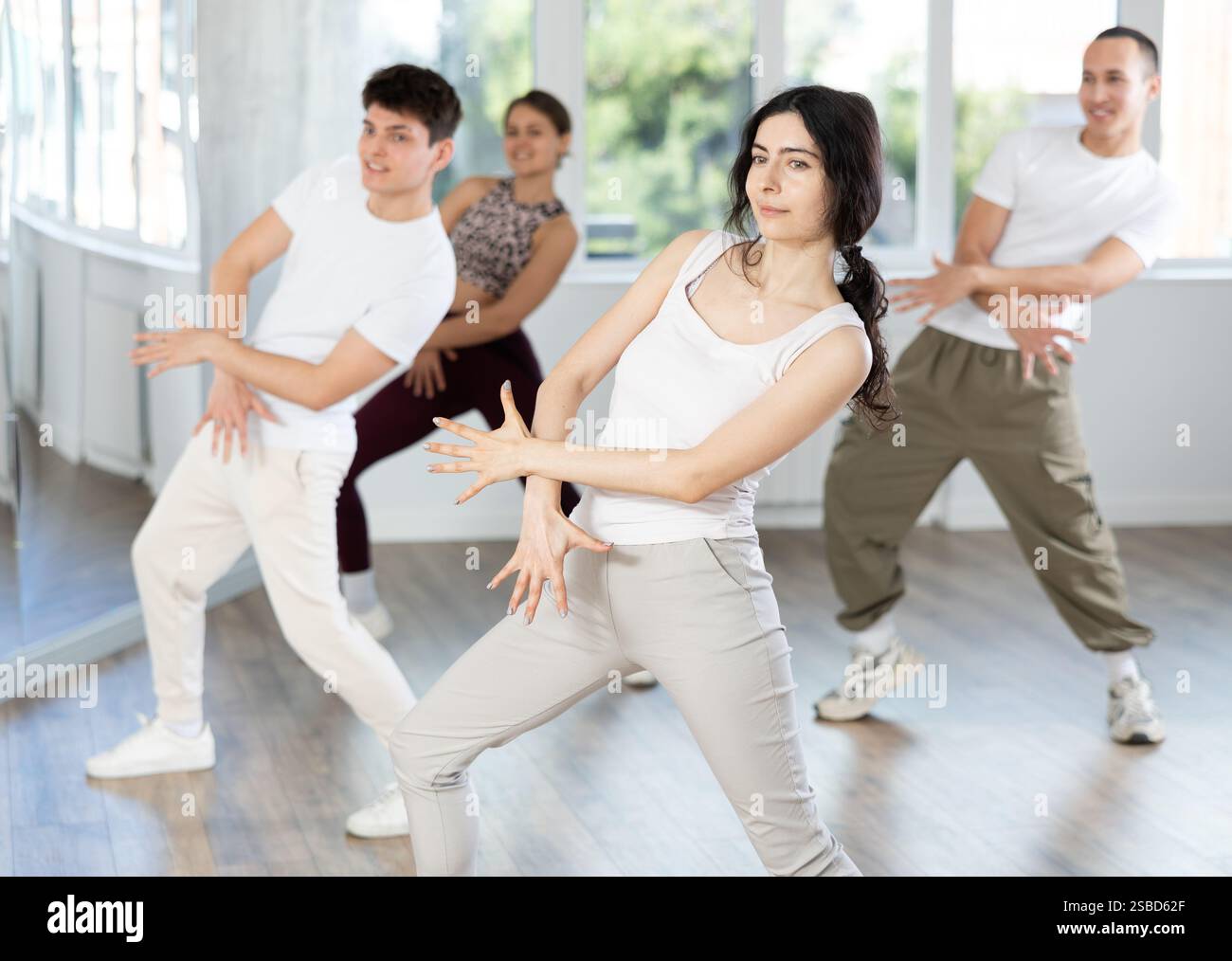 Emotional young female dancer rehearsing popping techniques in studio ...