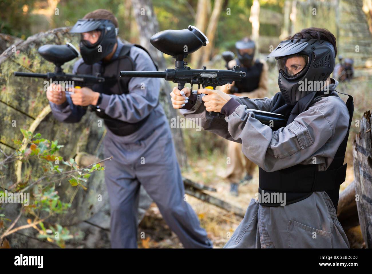 Paintball players aiming and shooting with guns at opposing team Stock ...