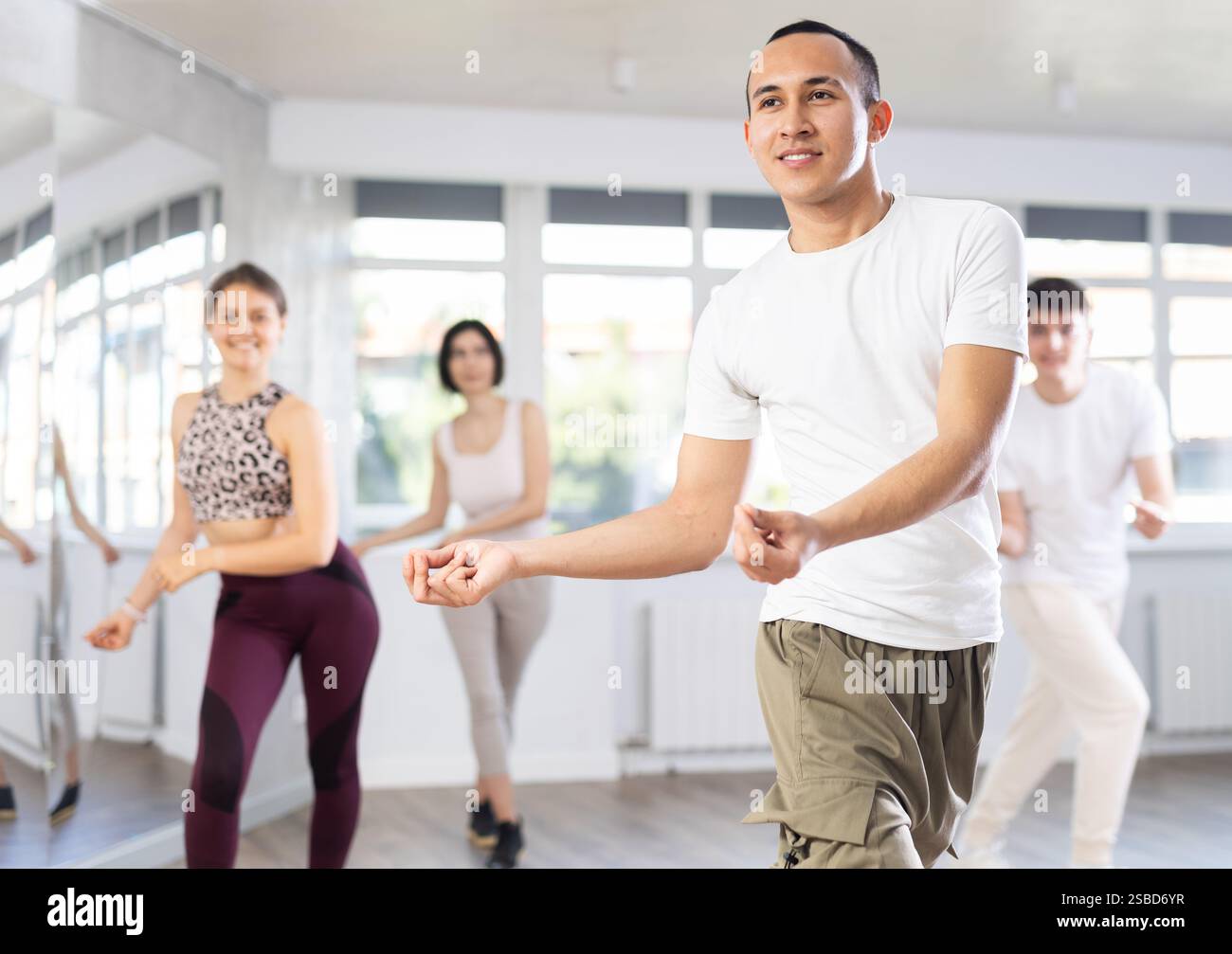 Positive guy and group of young active sport people practicing vogue ...