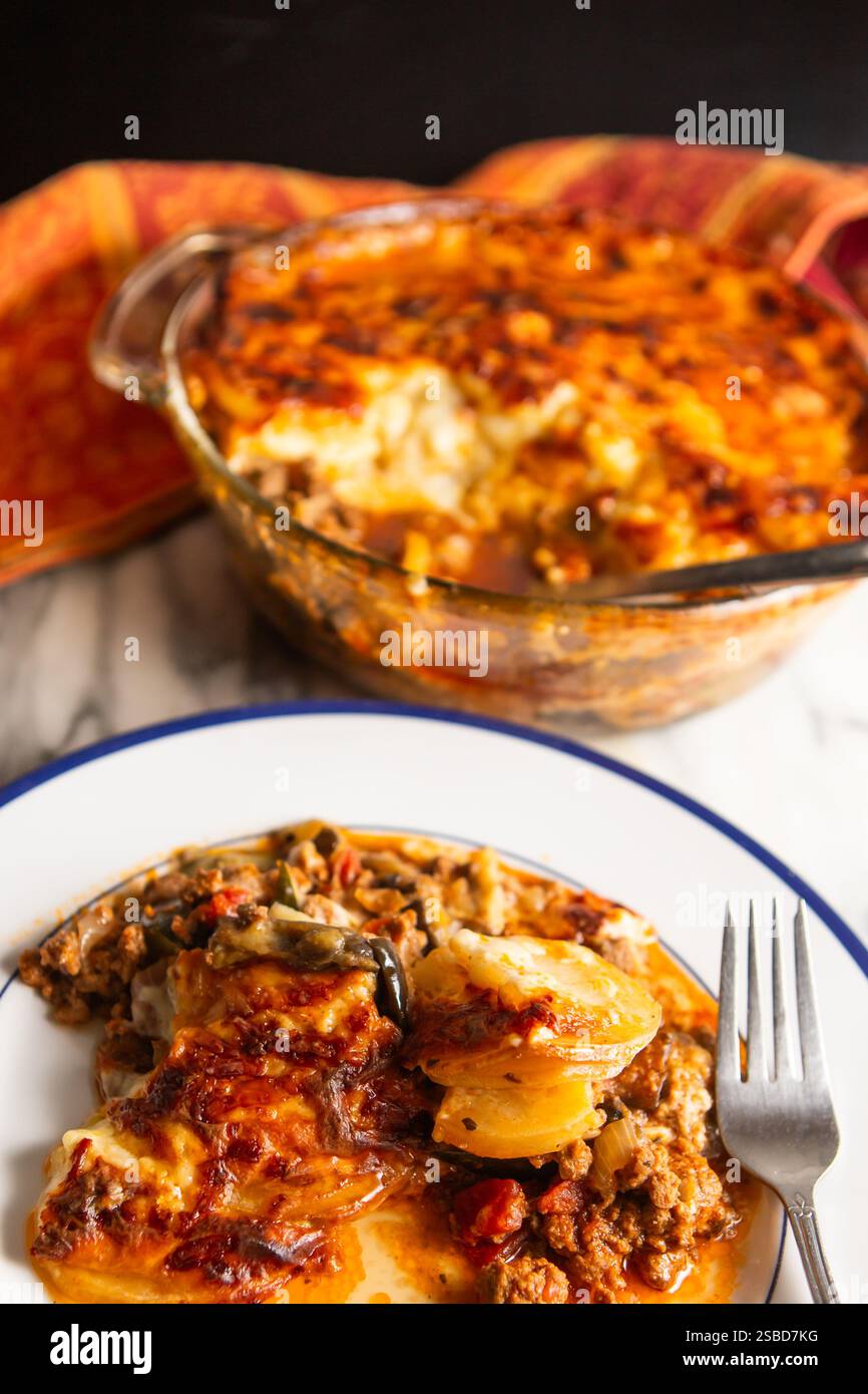 A serving of Homemade greek moussaka on a plate with cooked moussaka in ...
