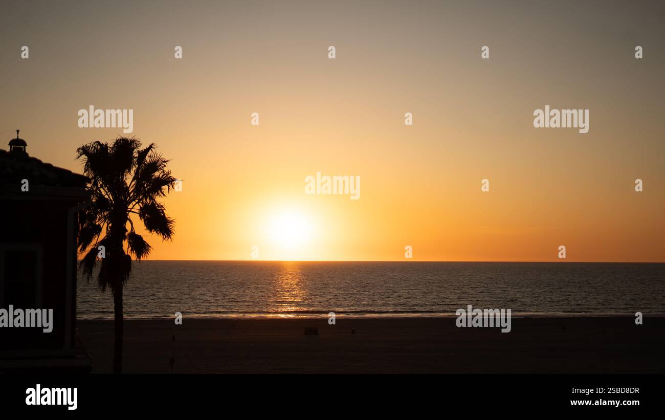 A mesmerizing sunset at Venice Beach, California, with the golden sun descending beyond the ...