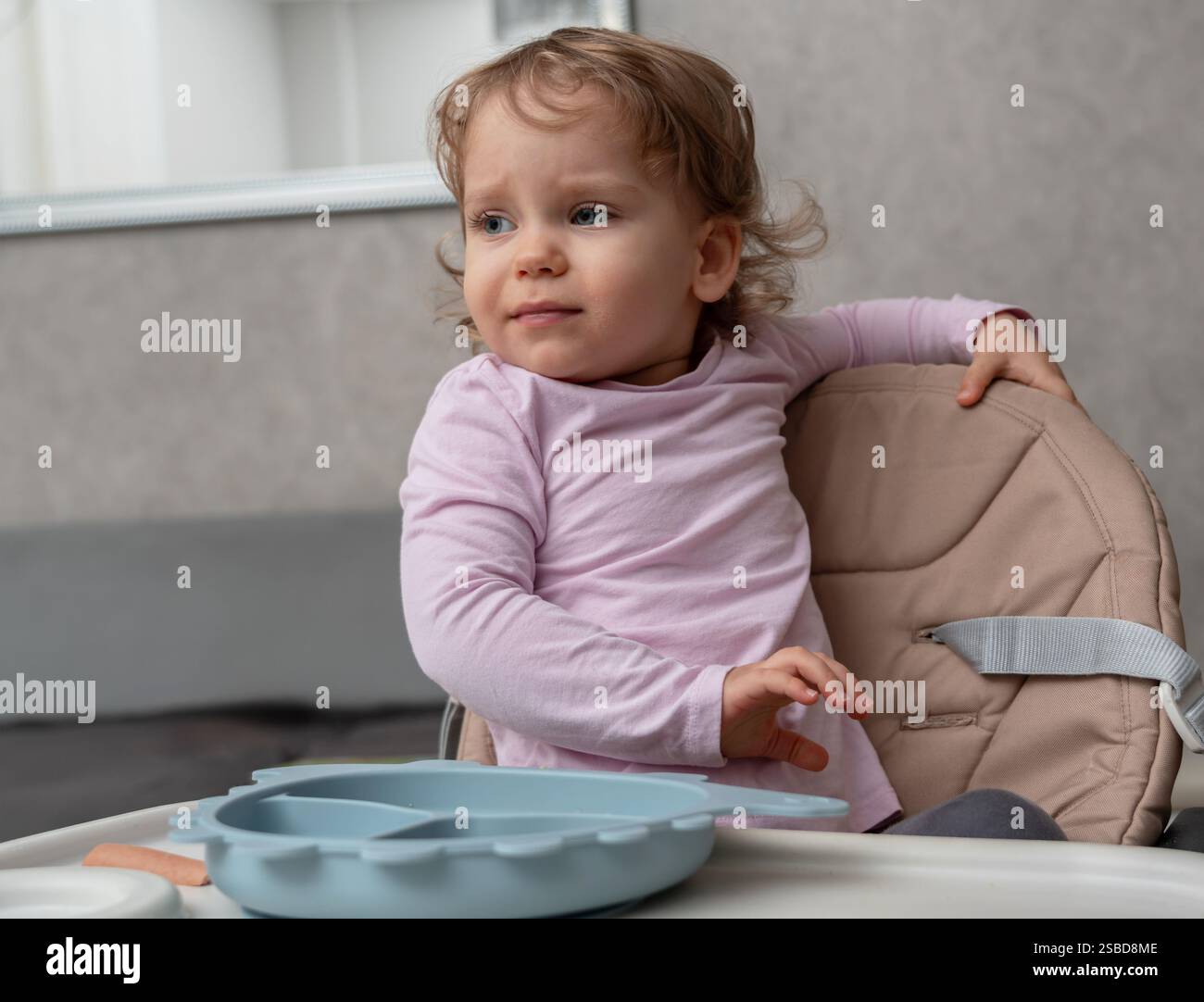 A curious toddler distracted during mealtime, showing independence and ...