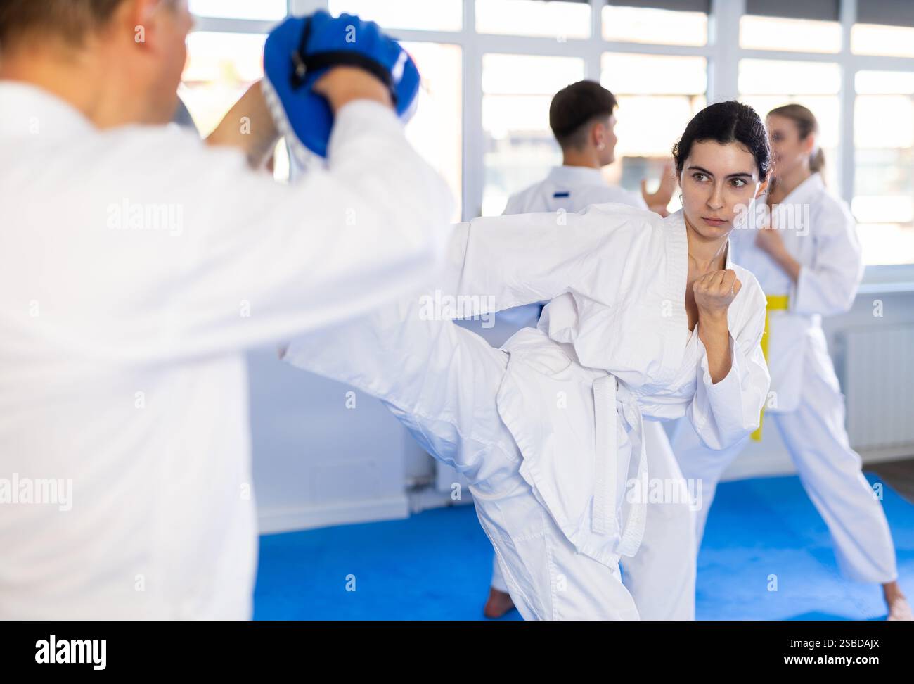arate trainer helps woman learn how to kick during karate training ...