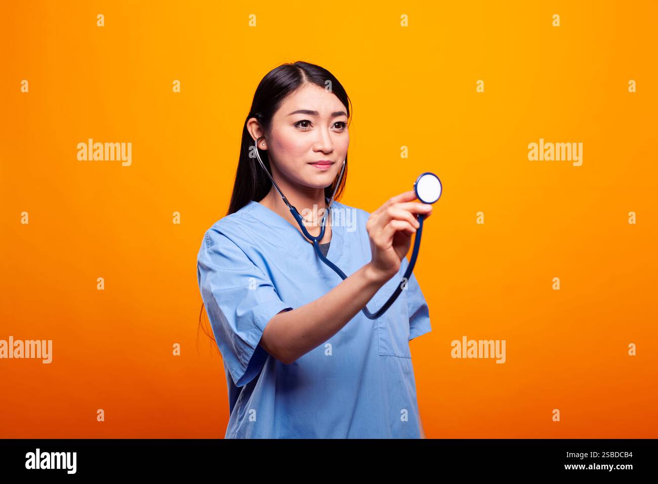 Female medic holding a stethoscope and standing in front of a yellow ...