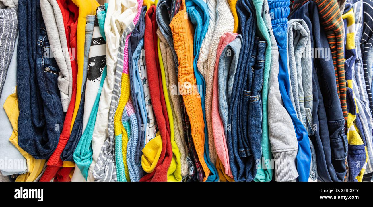 A very tall stack of folded colored clothes for charity, washing ...