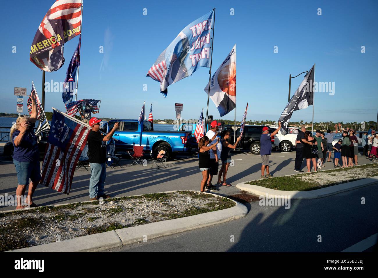 Supporters wave flags as a motorcade with President Donald Trump passes ...