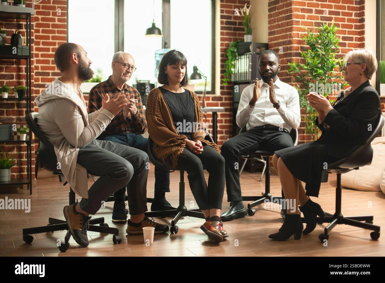Supportive community clapping for young woman during aa meeting in ...