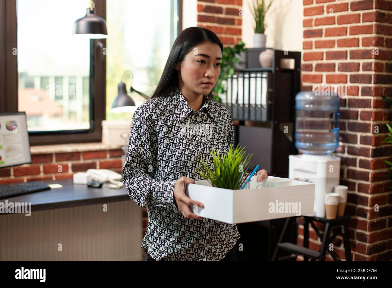 Asian businesswoman carrying a box of office materials and leaving ...