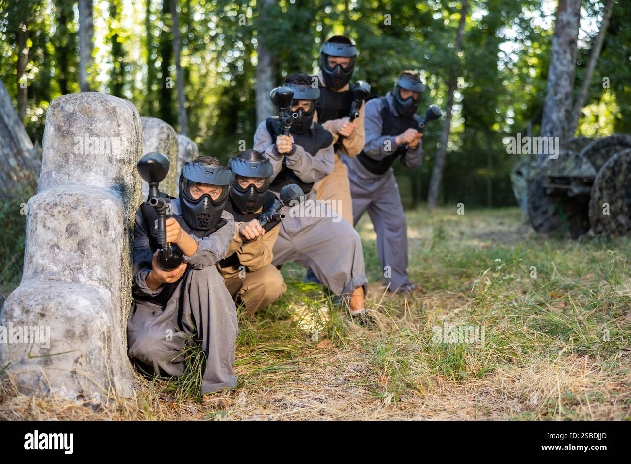Group of paintball players aiming and shooting with guns outdoors Stock ...