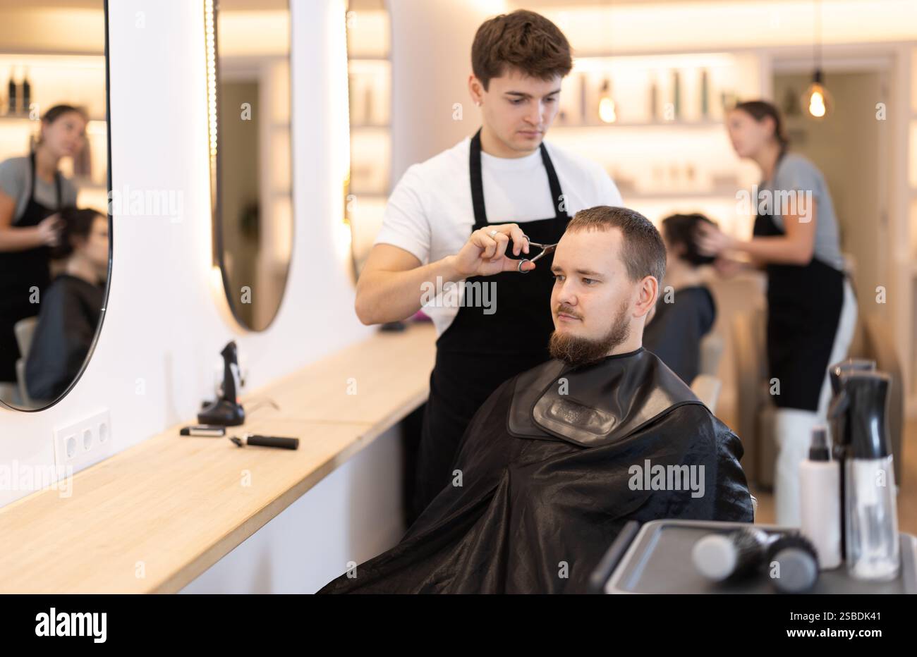 Young guy hairdresser giving haircut to young man Stock Photo - Alamy