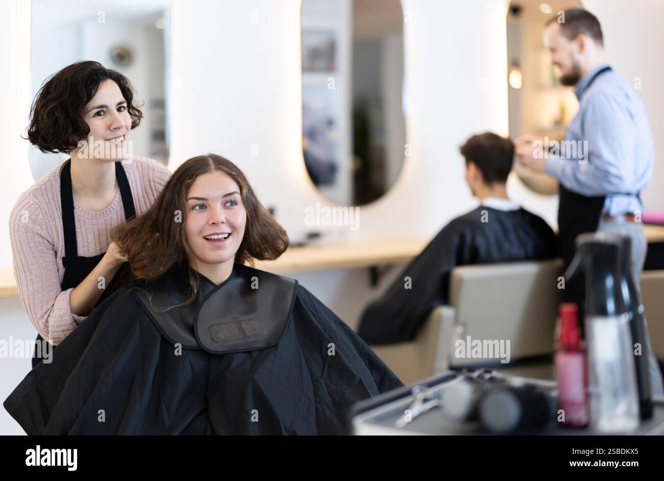 Young woman barbershop employee stands next to female client ...