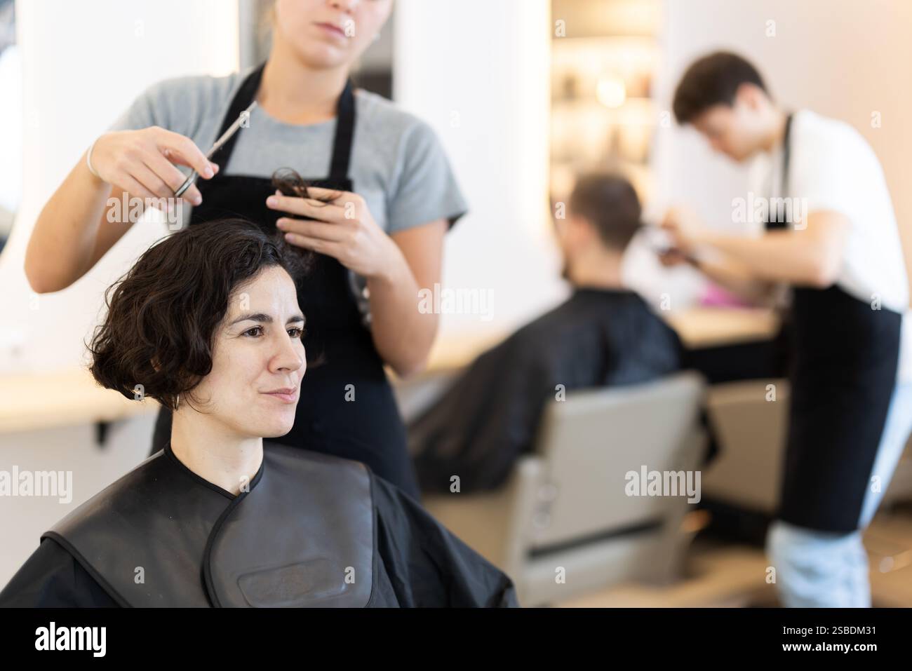 Female hairdresser giving haircut to adult woman Stock Photo - Alamy