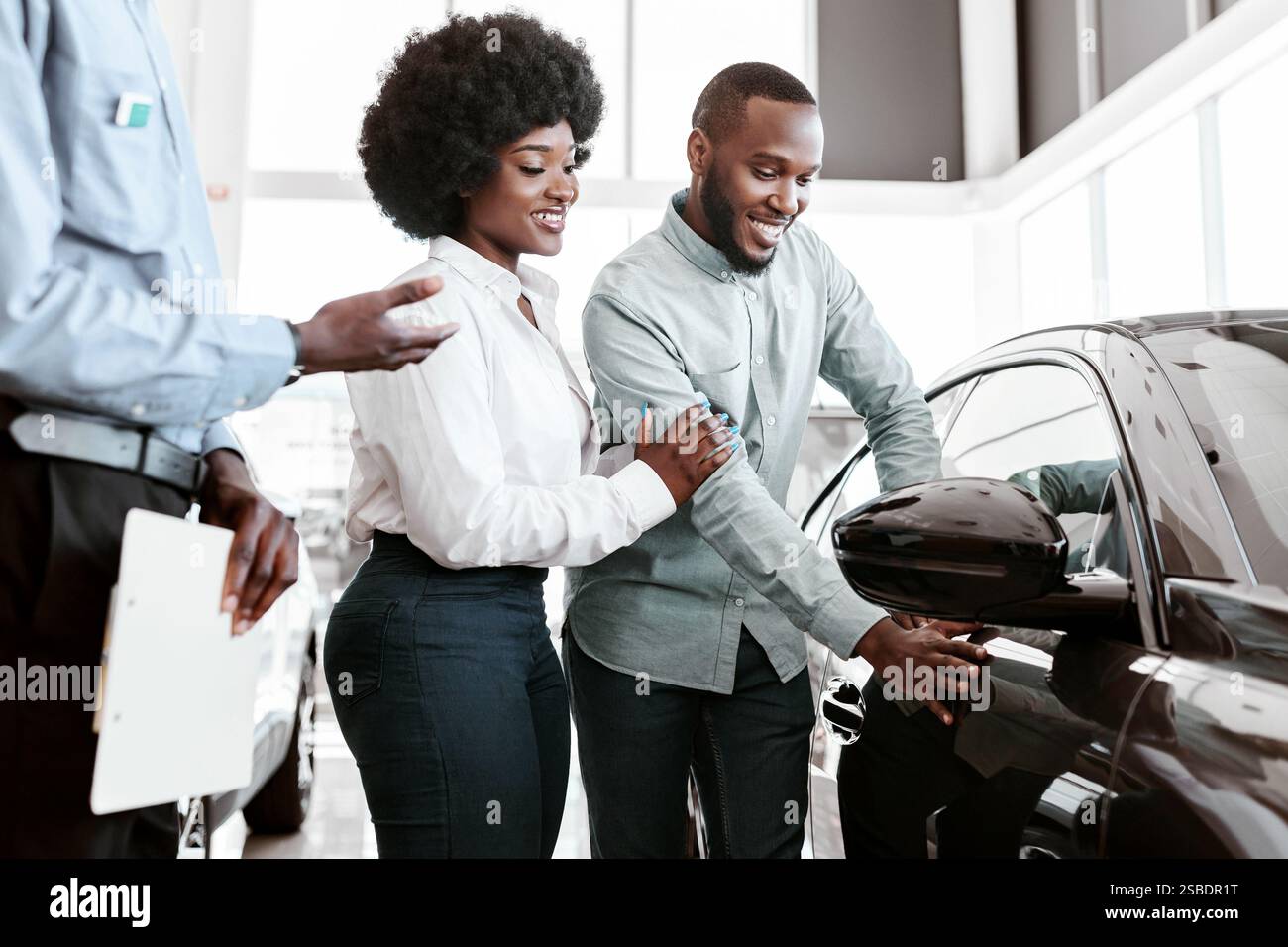 Car sales business. Manager talking to Afro couple, showing them new ...