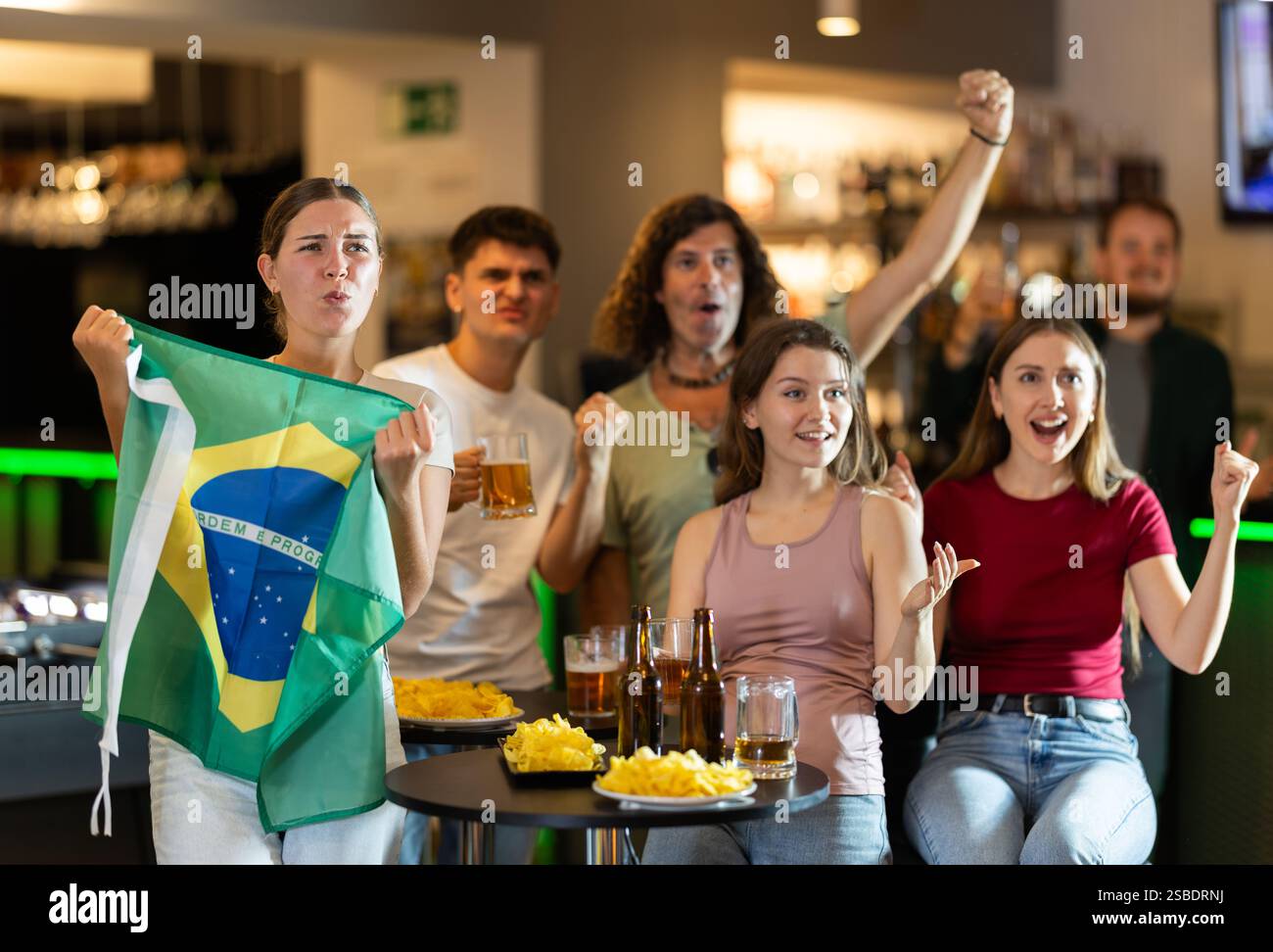 Brazilian fans with the national flag watch match on TV and express ...