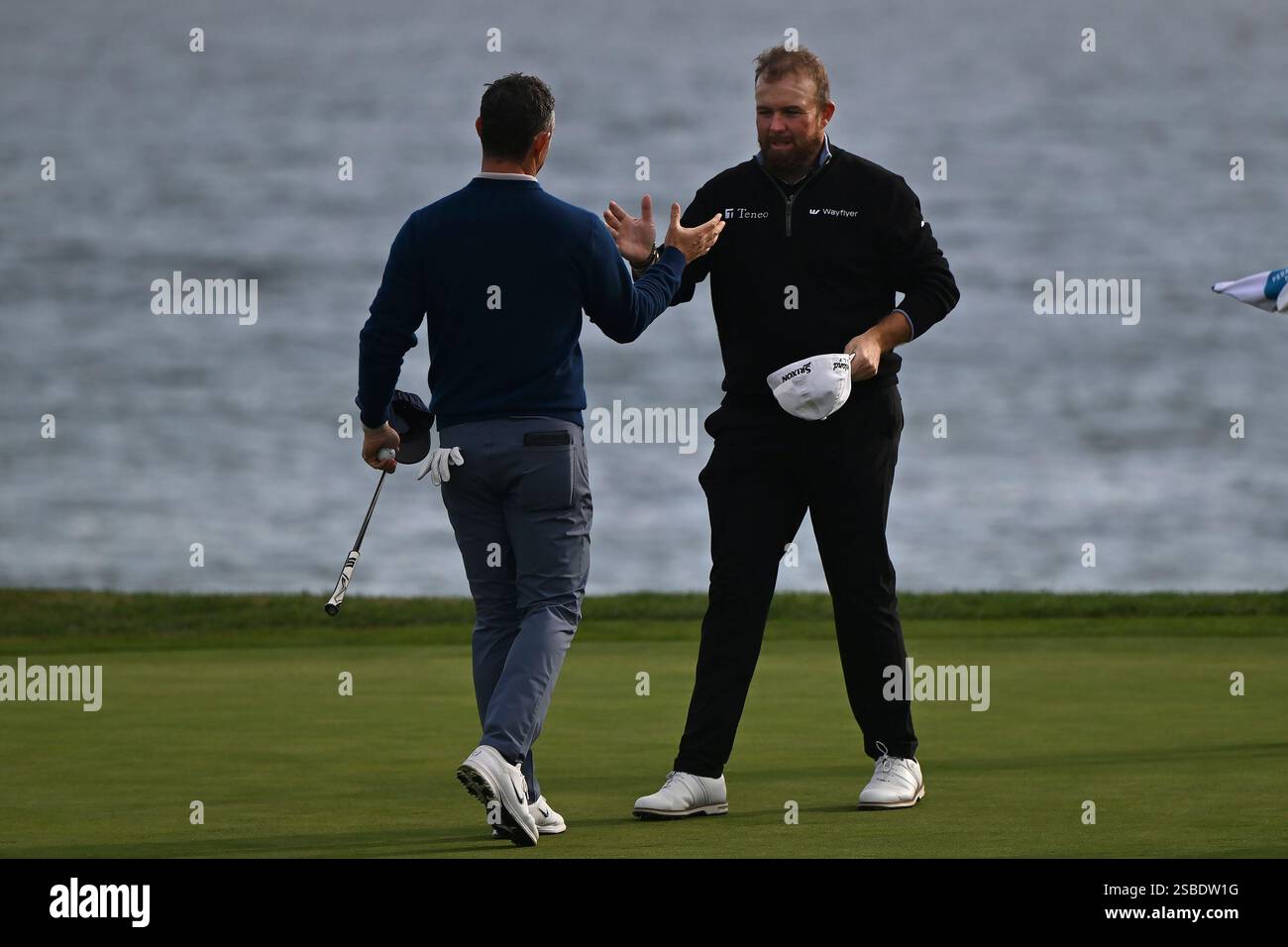 Rory McIlroy, of Northern Ireland, left, shakes hands with Shane Lowry after completing the 18th ...