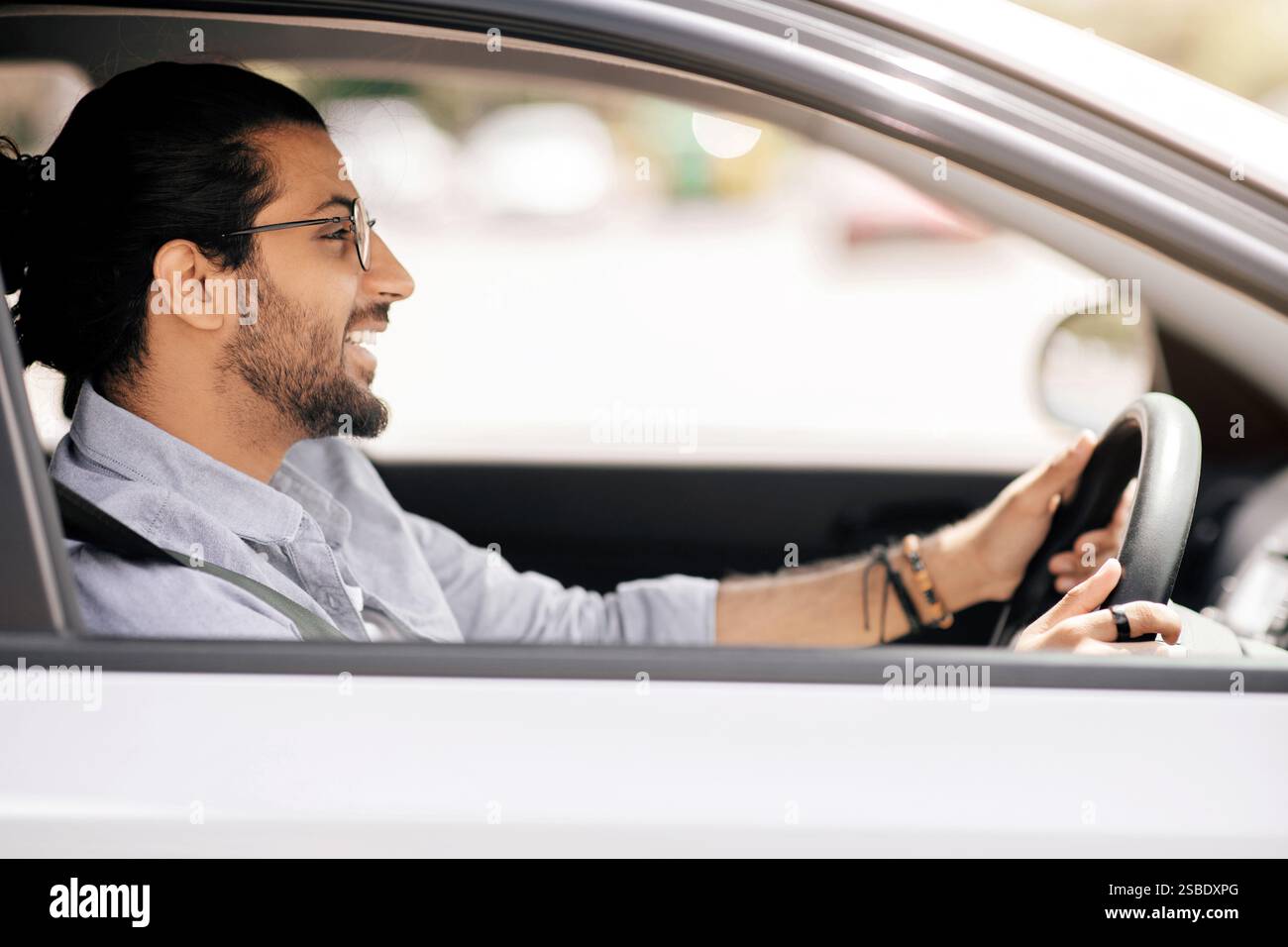 Handsome millennial arabic guy driving car, side view Stock Photo - Alamy