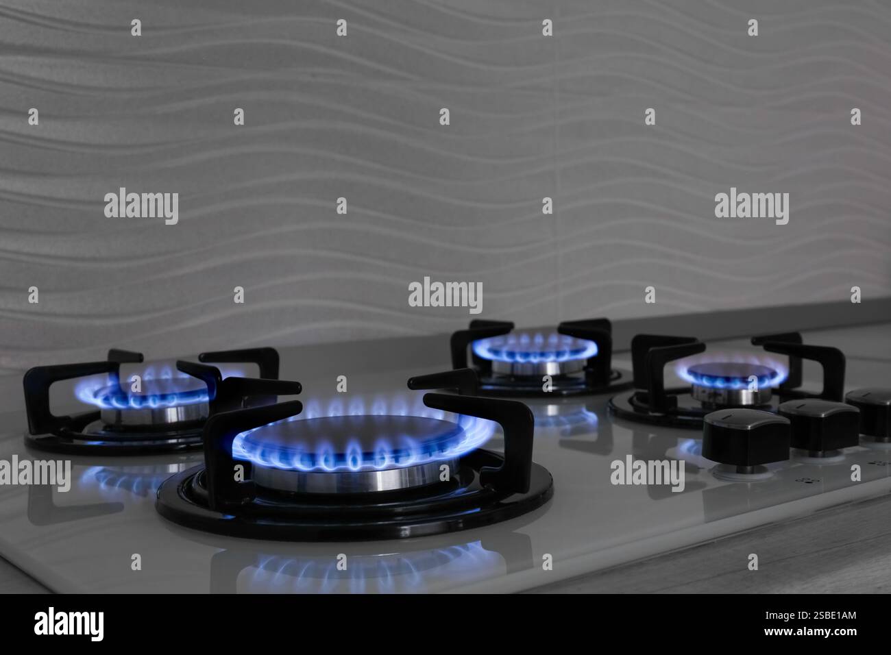 Modern gas cooktop with burning blue flames in kitchen Stock Photo - Alamy