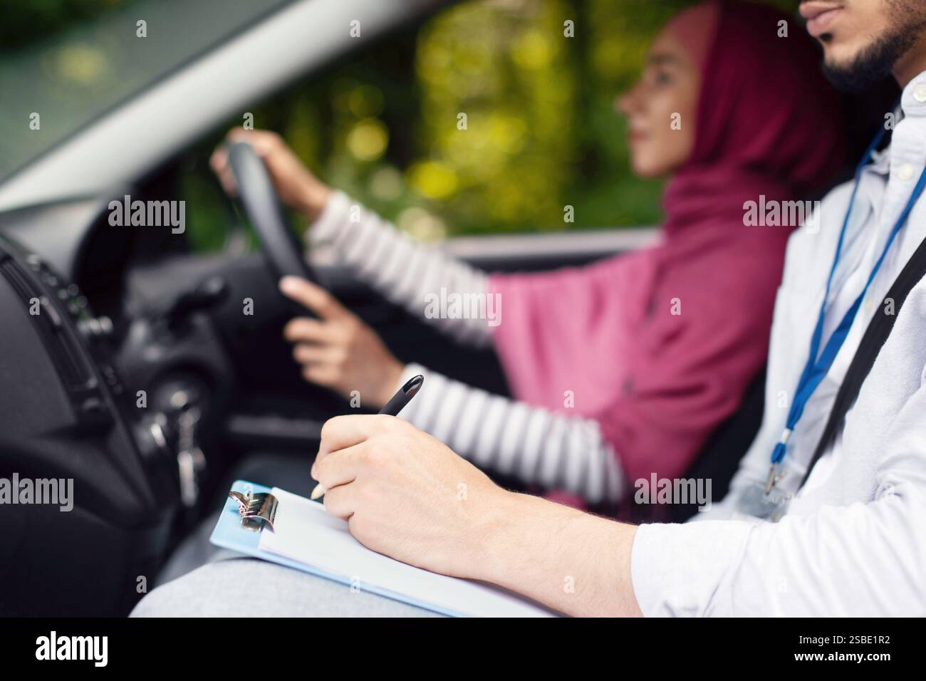 Driving School Concept. Male instructor examining muslim lady driver ...