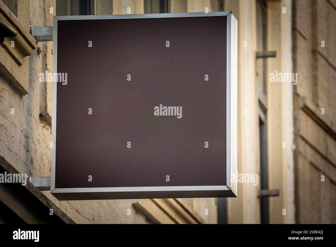 Selective blur on A rectangular black sign stands blank outside a store ...