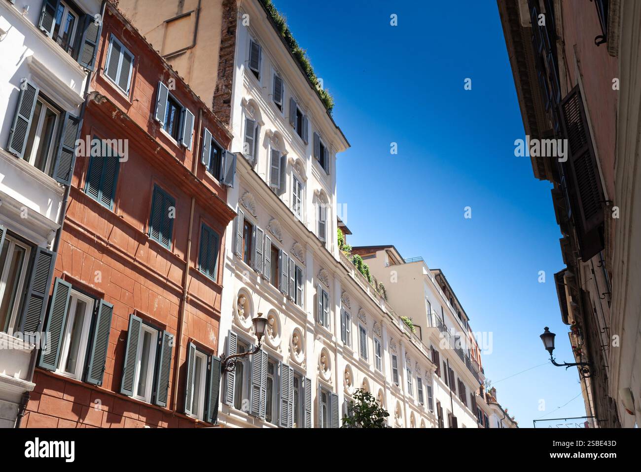 Sunlit facades of old residential buildings display faded plaster and ...