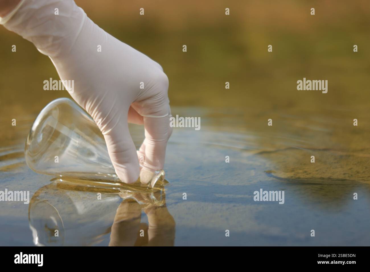Examination of water quality. Researcher taking water sample from lake ...