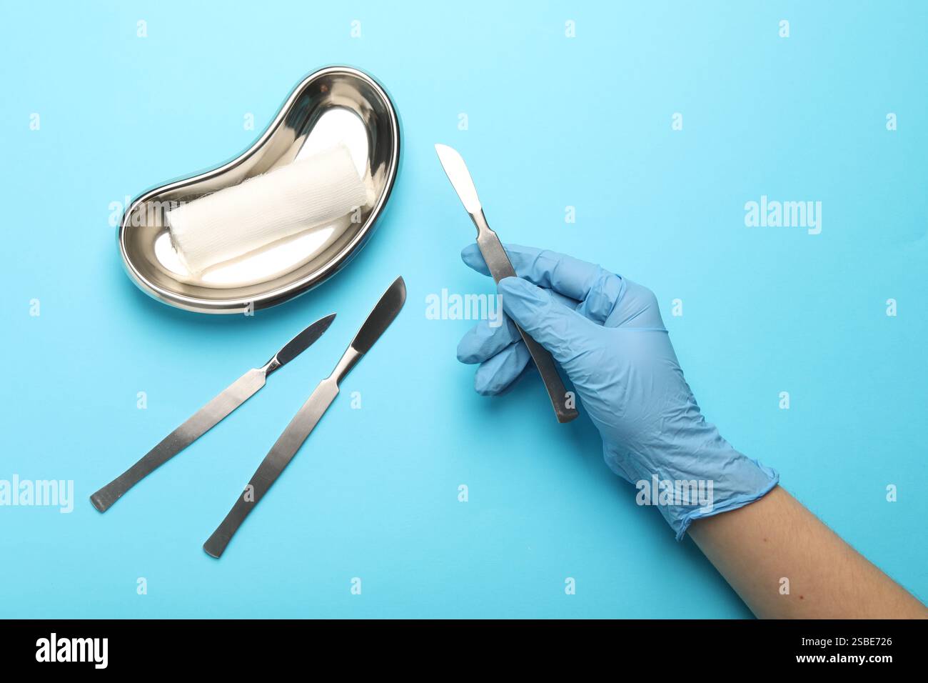 Doctor with surgical scalpels on light blue background, top view Stock ...