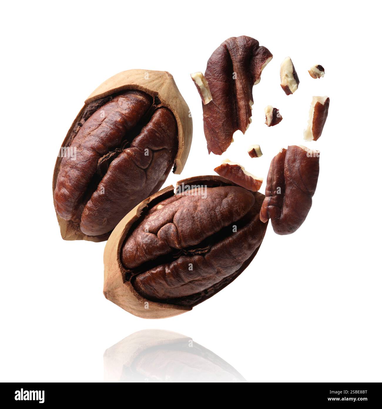 Broken pecan nuts in air on white background Stock Photo - Alamy
