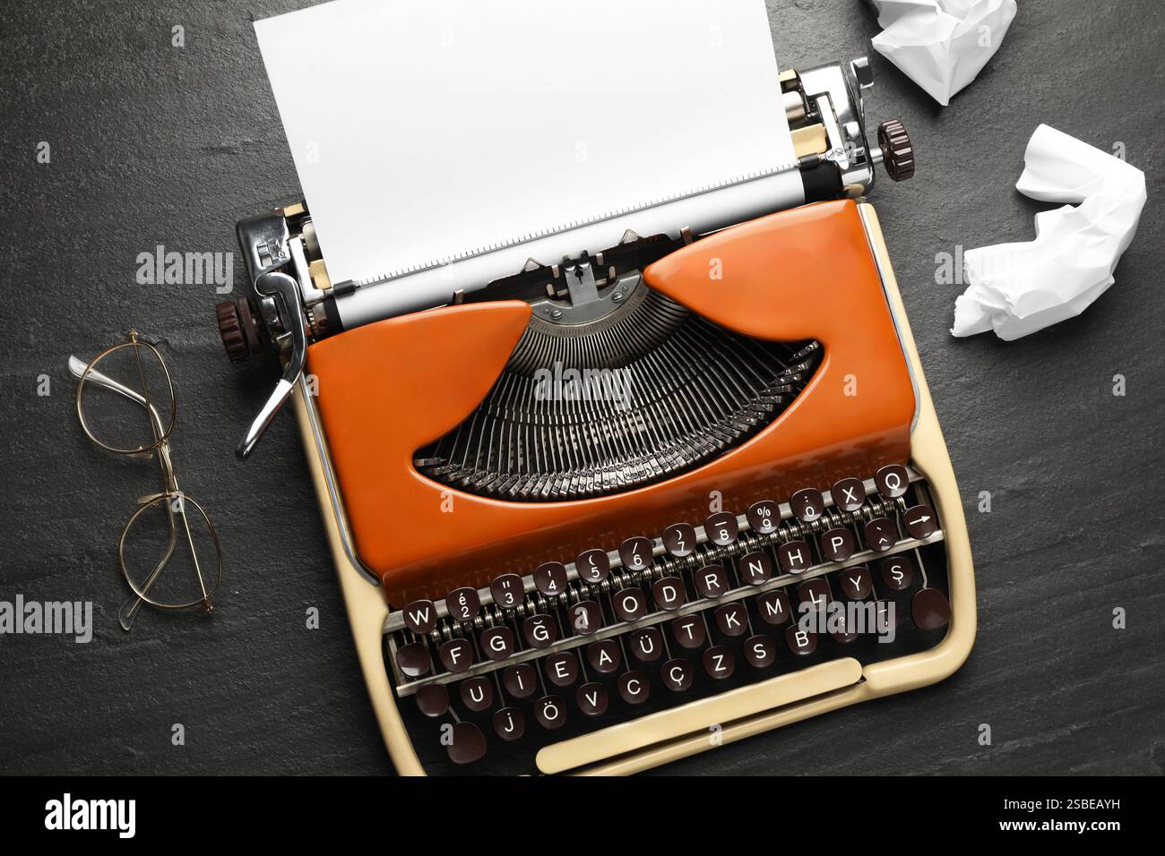 Vintage typewriter with sheet and crumpled paper on black background ...