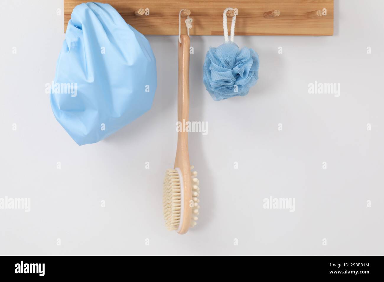 Shower cap, brush and mesh sponge on rack indoors Stock Photo - Alamy