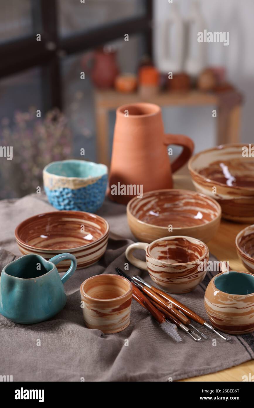 Different beautiful pottery and set of clay crafting tools on table ...