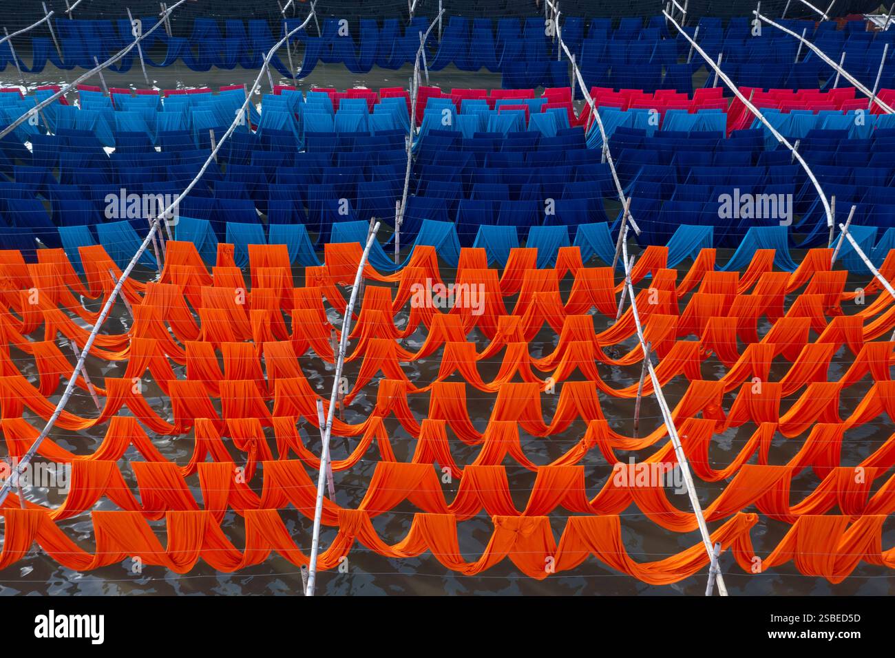 An aerial view captures freshly dyed fabrics drying under the open sky ...