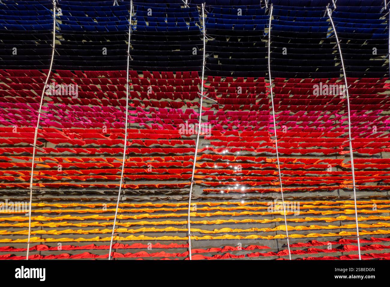An aerial view captures freshly dyed fabrics drying under the open sky ...
