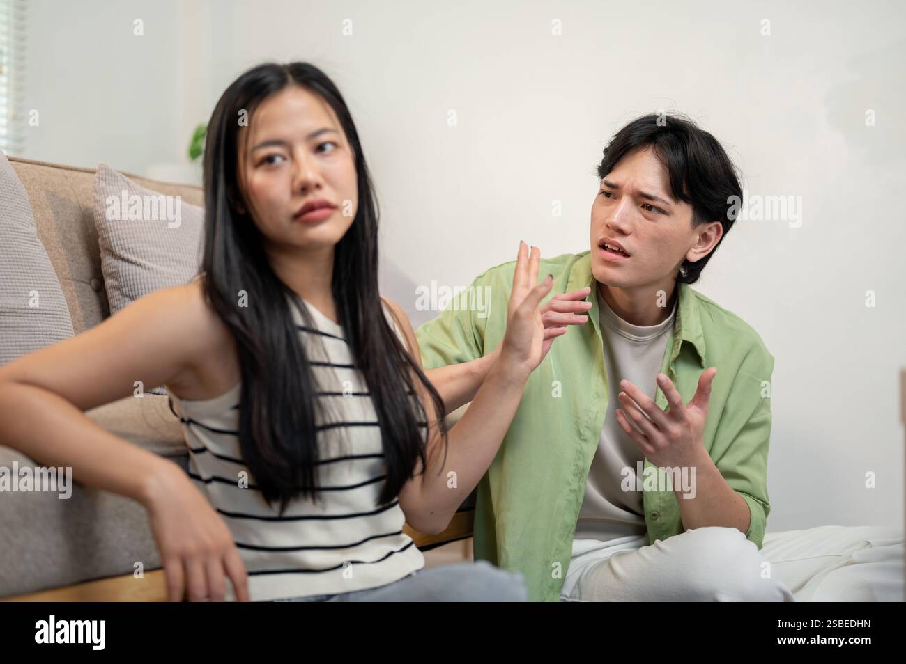 A toxic relationship in a young couple. An unhappy Asian couple sits in ...