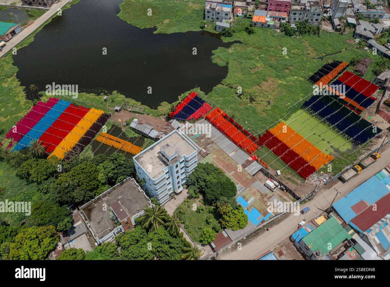 An aerial view captures freshly dyed fabrics drying under the open sky ...