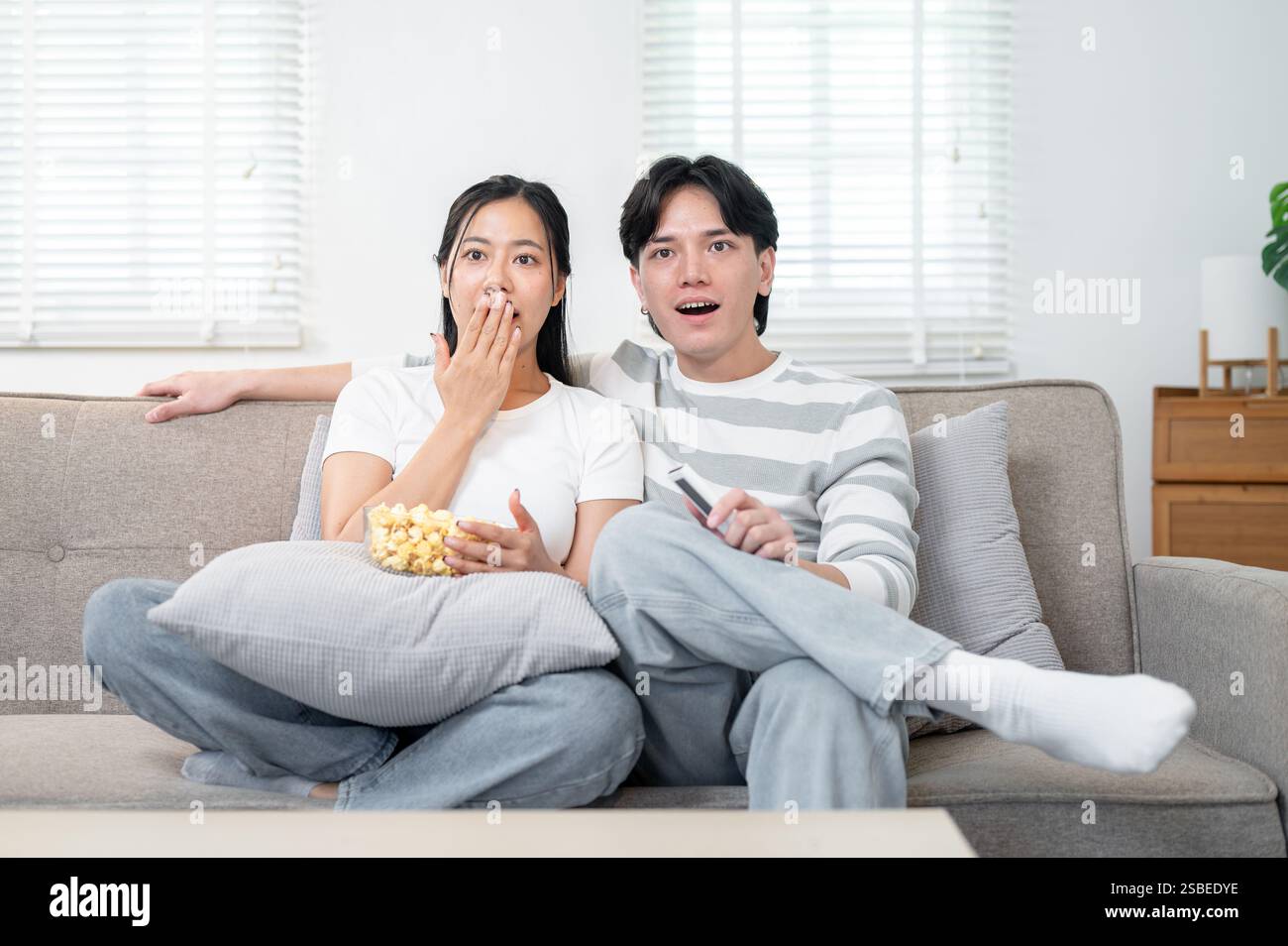Happy young Asian boyfriend and girlfriend enjoy watching a movie on ...