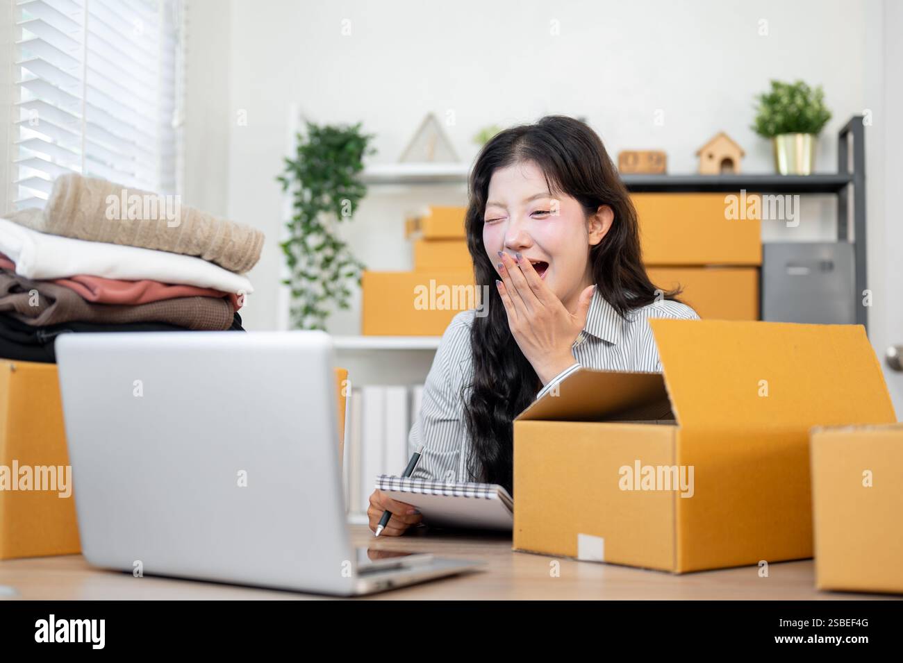 A tired, sleepy Asian female inventory staff member is exhausted from a ...
