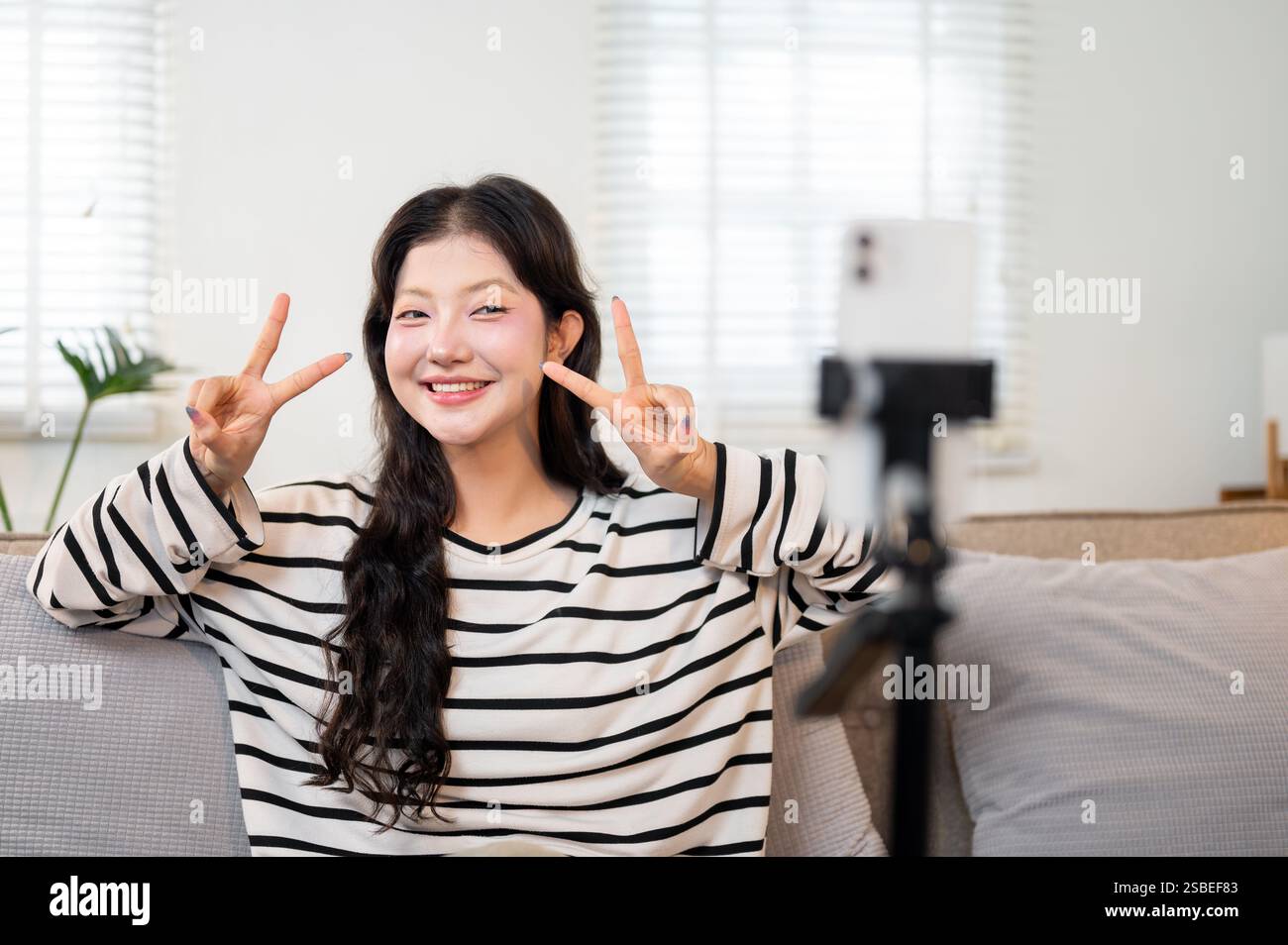 An attractive, confident Asian female content creator is recording a ...