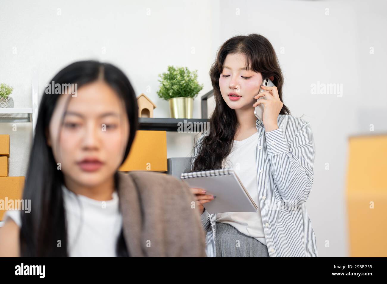 A beautiful, positive Asian female inventory staff member is talking on ...