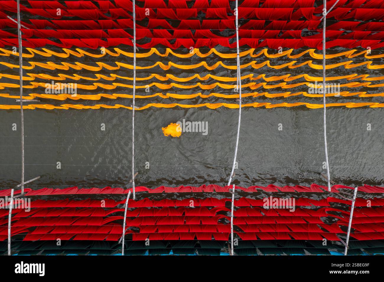 An aerial view captures freshly dyed fabrics drying under the open sky ...