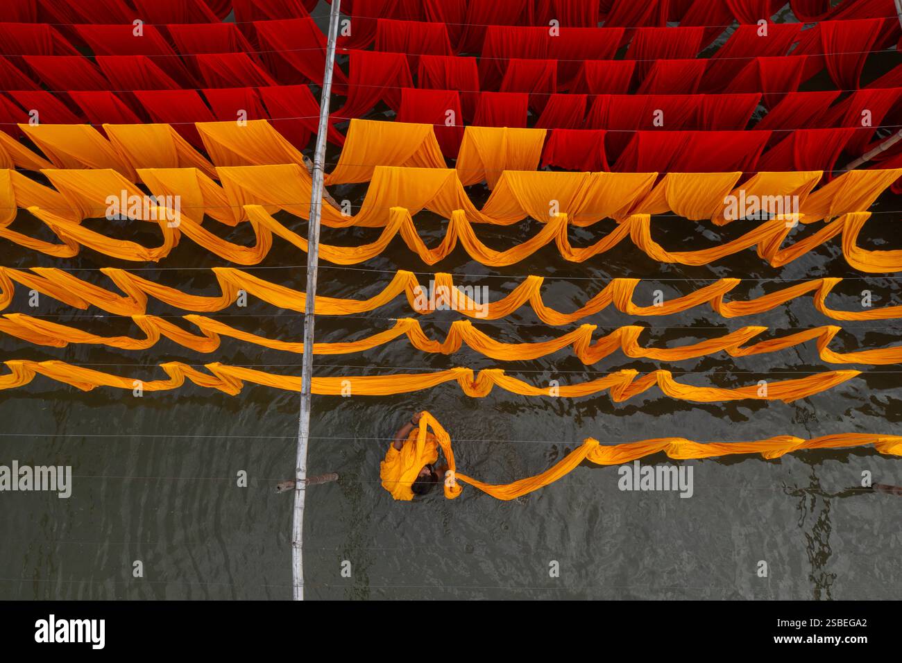 An aerial view captures freshly dyed fabrics drying under the open sky ...